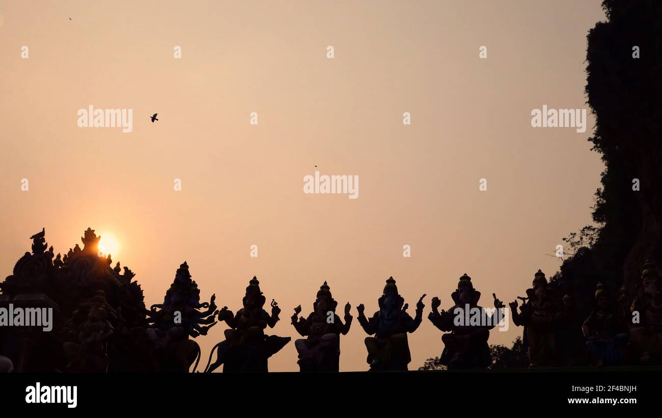 Hindu Statues In Silhouette At Sunset : Religious statues at Batu Caves ...