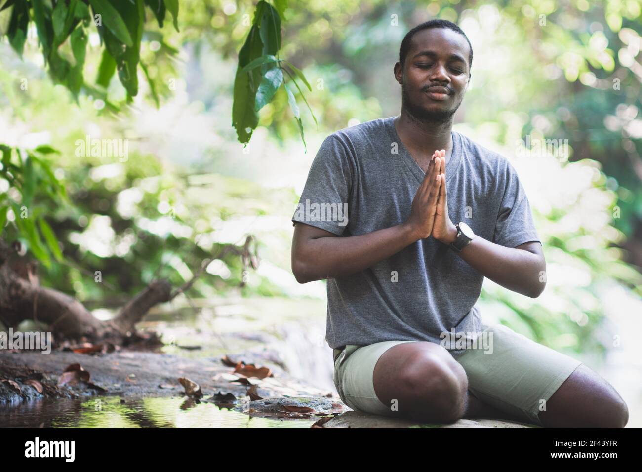 African man meditate spiritual peaceful praying and wishing in green ...