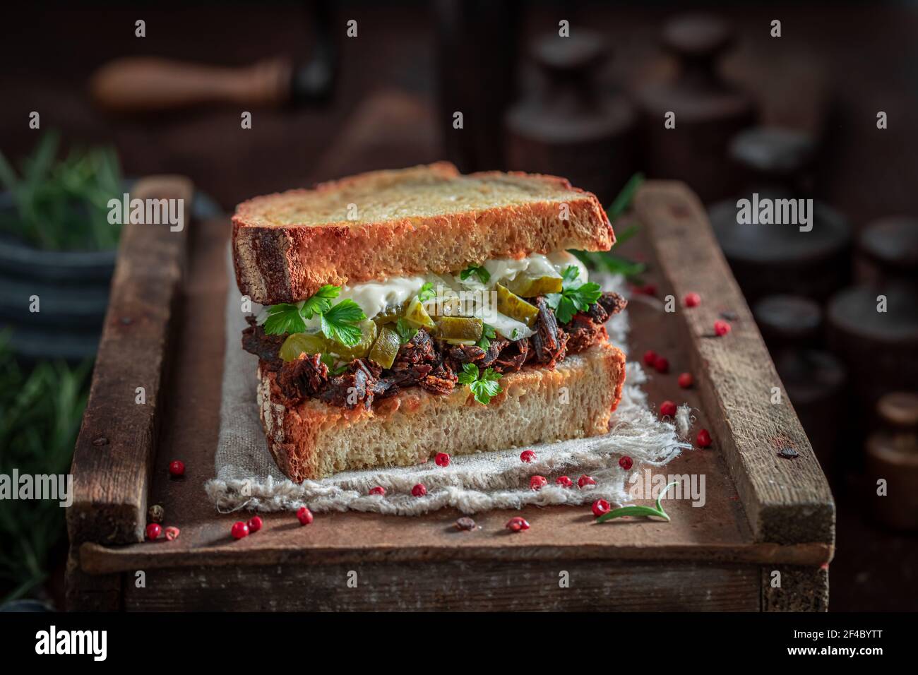 Homemade sandwich with shredded beef and gherkin with herbs and sauce ...