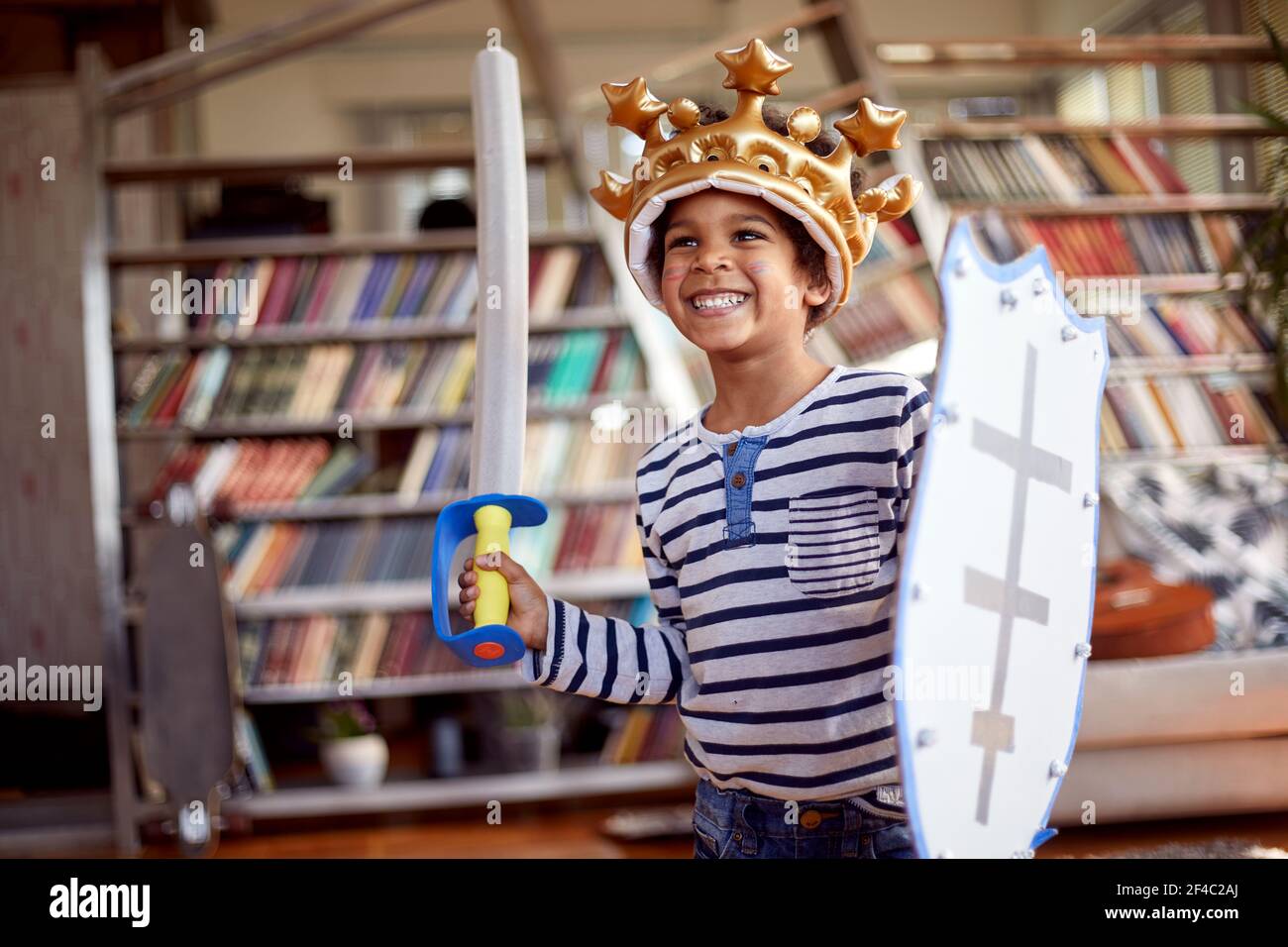 A cute little boy dressed as knight is posing for a photo while playing ...