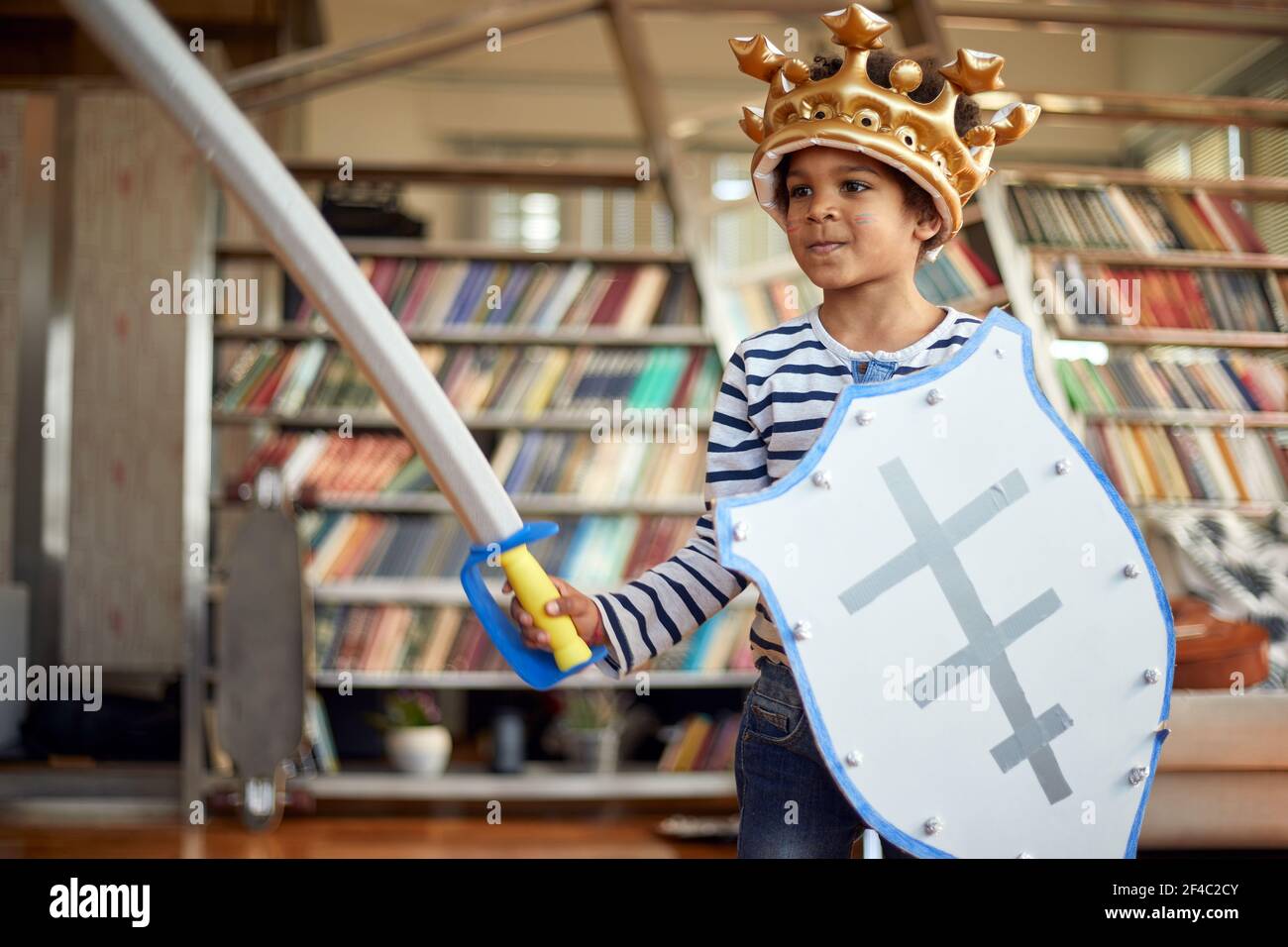A cheerful little boy posing with a sword and a shield while playing in ...
