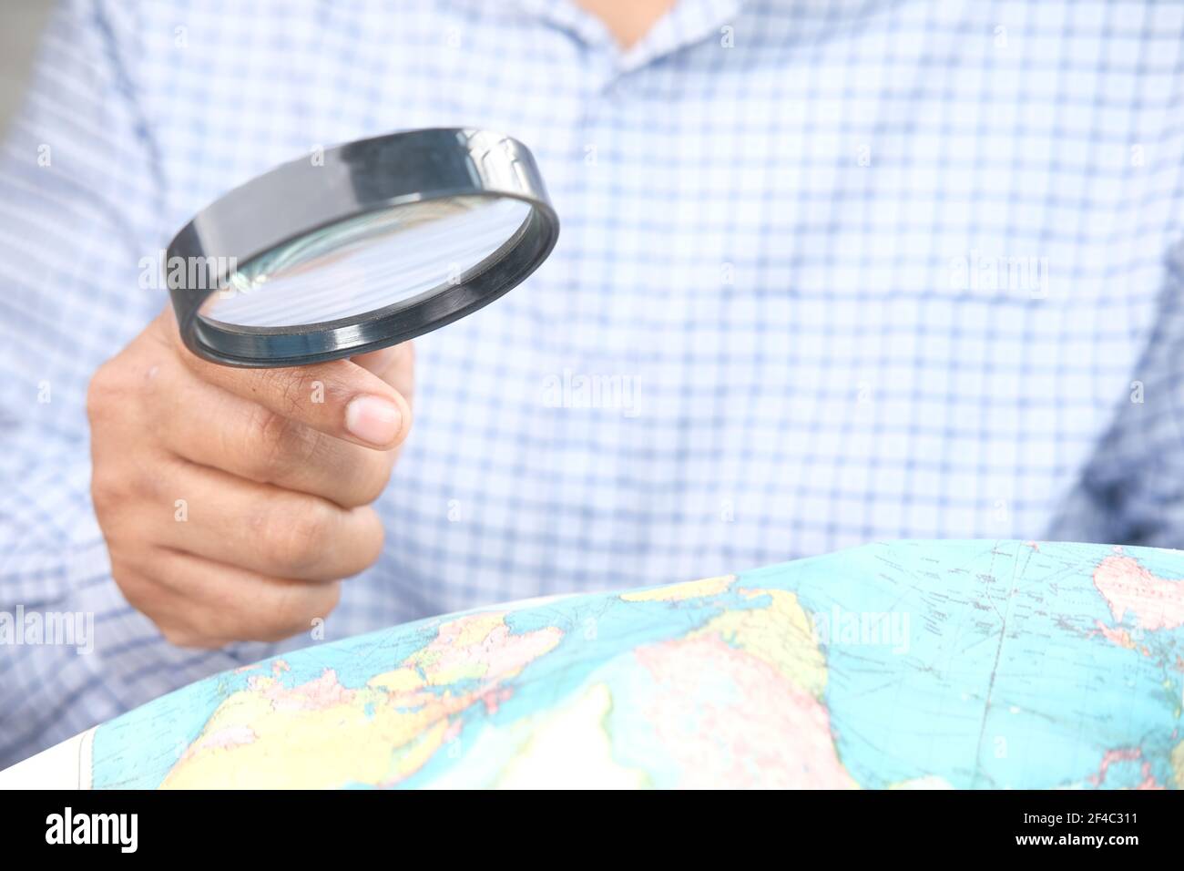 young man using magnifying glass looking something on map Stock Photo ...