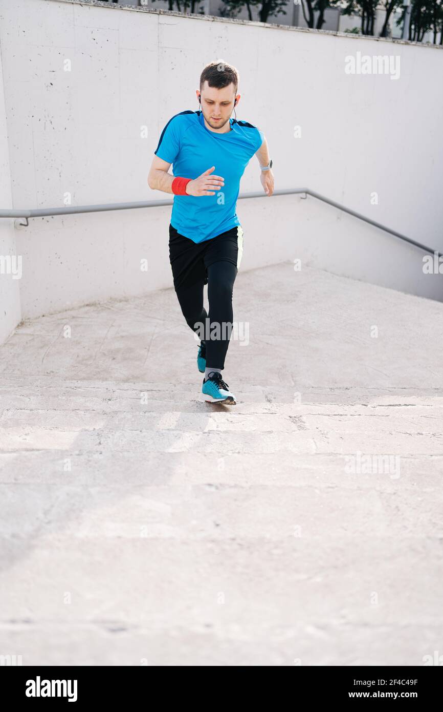 Young man running upstairs on city stairs. Fitness, sport, people ...
