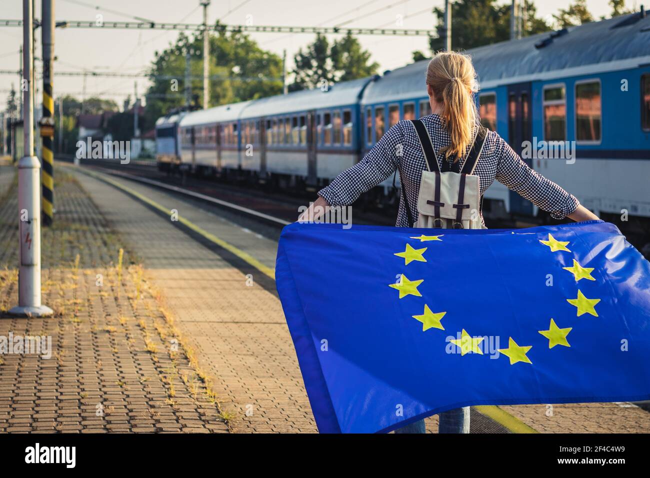 Travel by train. Backpacker woman with EU flag standing on railroad ...