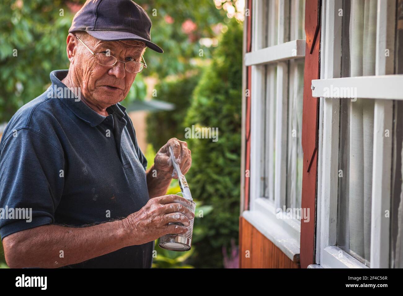 Active senior man painting house exterior. Old craftsperson repairing ...