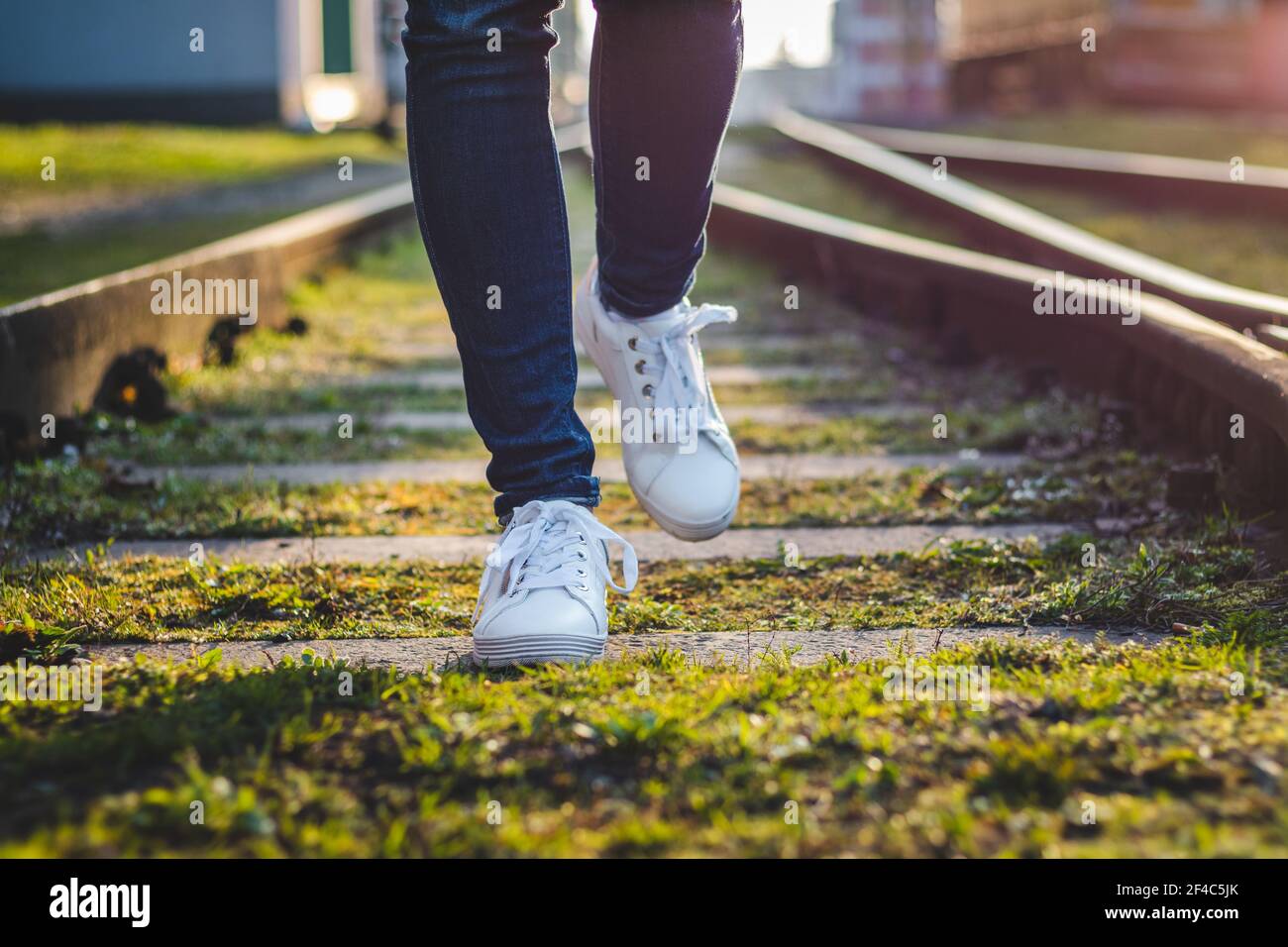 Woman wearing white sneakers running on railroad track. Female legs ...