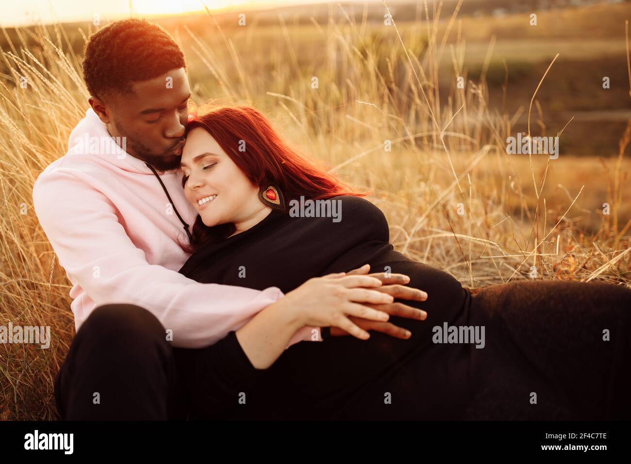 Adorable couple lay at the field, attractive husband gently hug ...