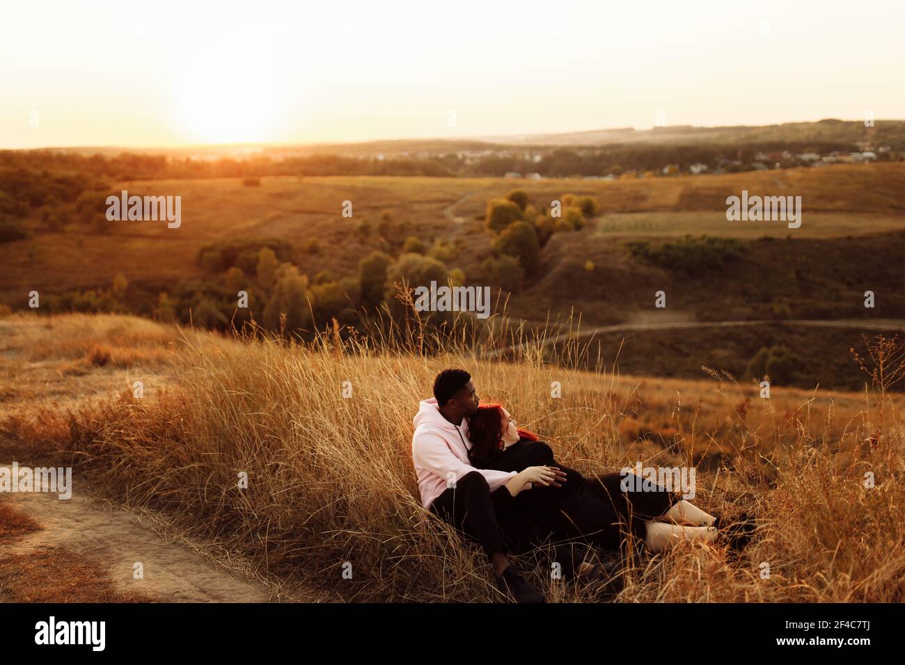 Happy couple lay at the field, loving husband gently hug adorable wife ...