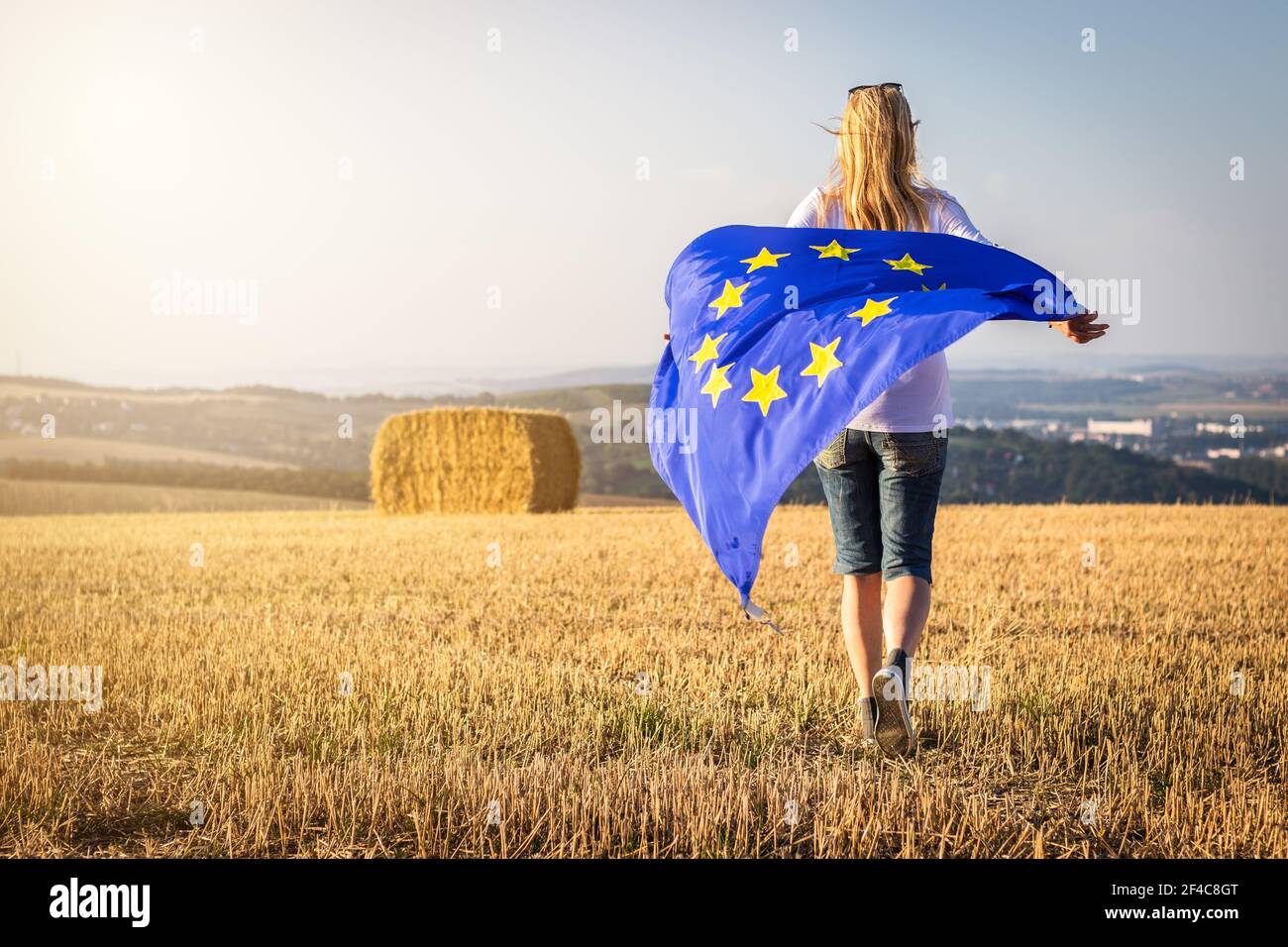 Woman running with waving european union flag in countryside. EU flag ...