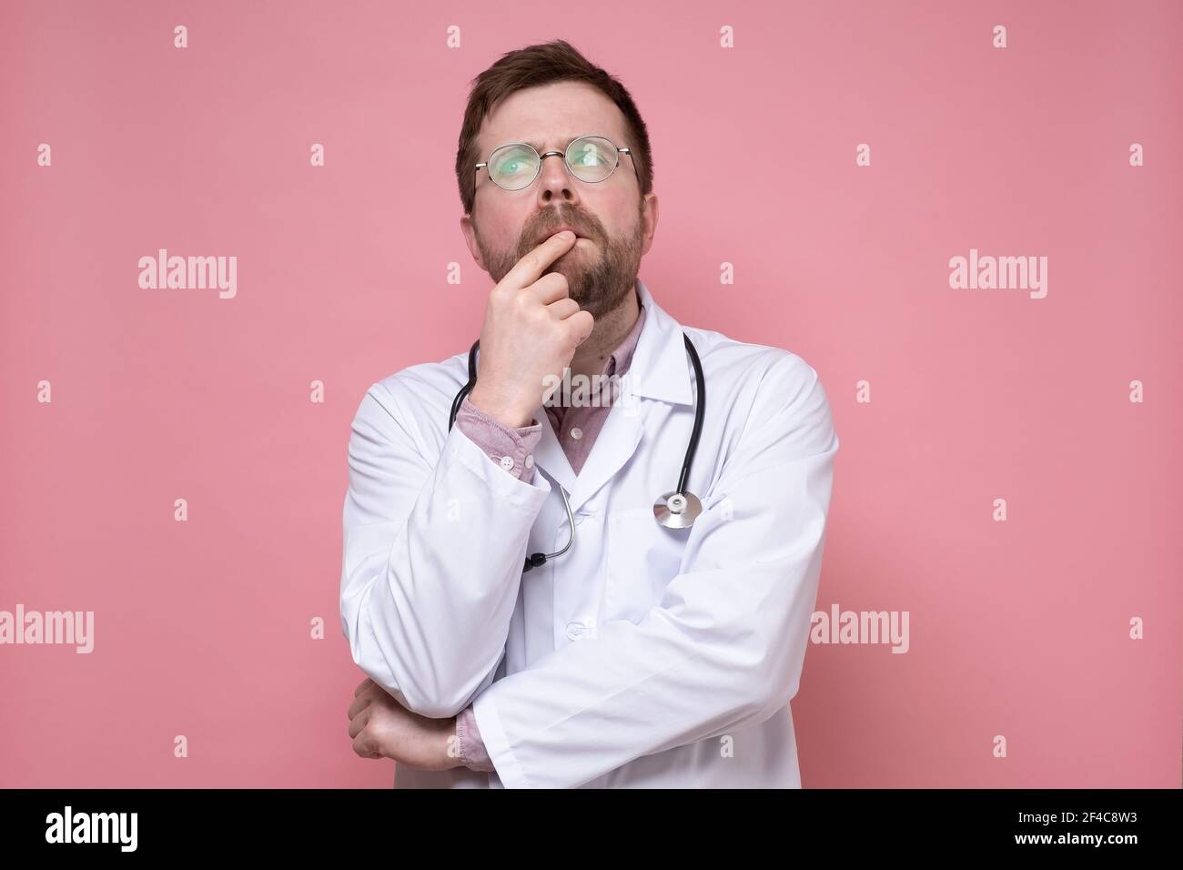 Puzzled male doctor with glasses, a white coat and a stethoscope around ...