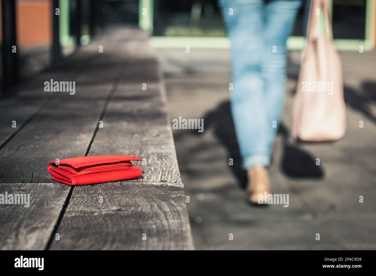 Woman is leaving from a bench where she forgot her leather wallet. Lost ...