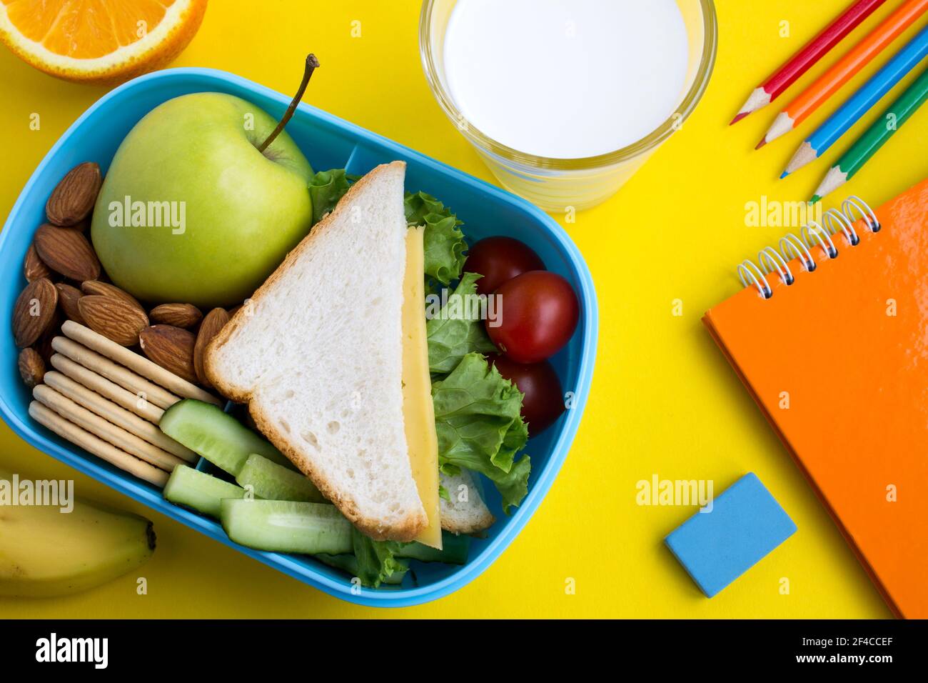 School lunch in the box, milk in the glass and notebook on the yellow ...