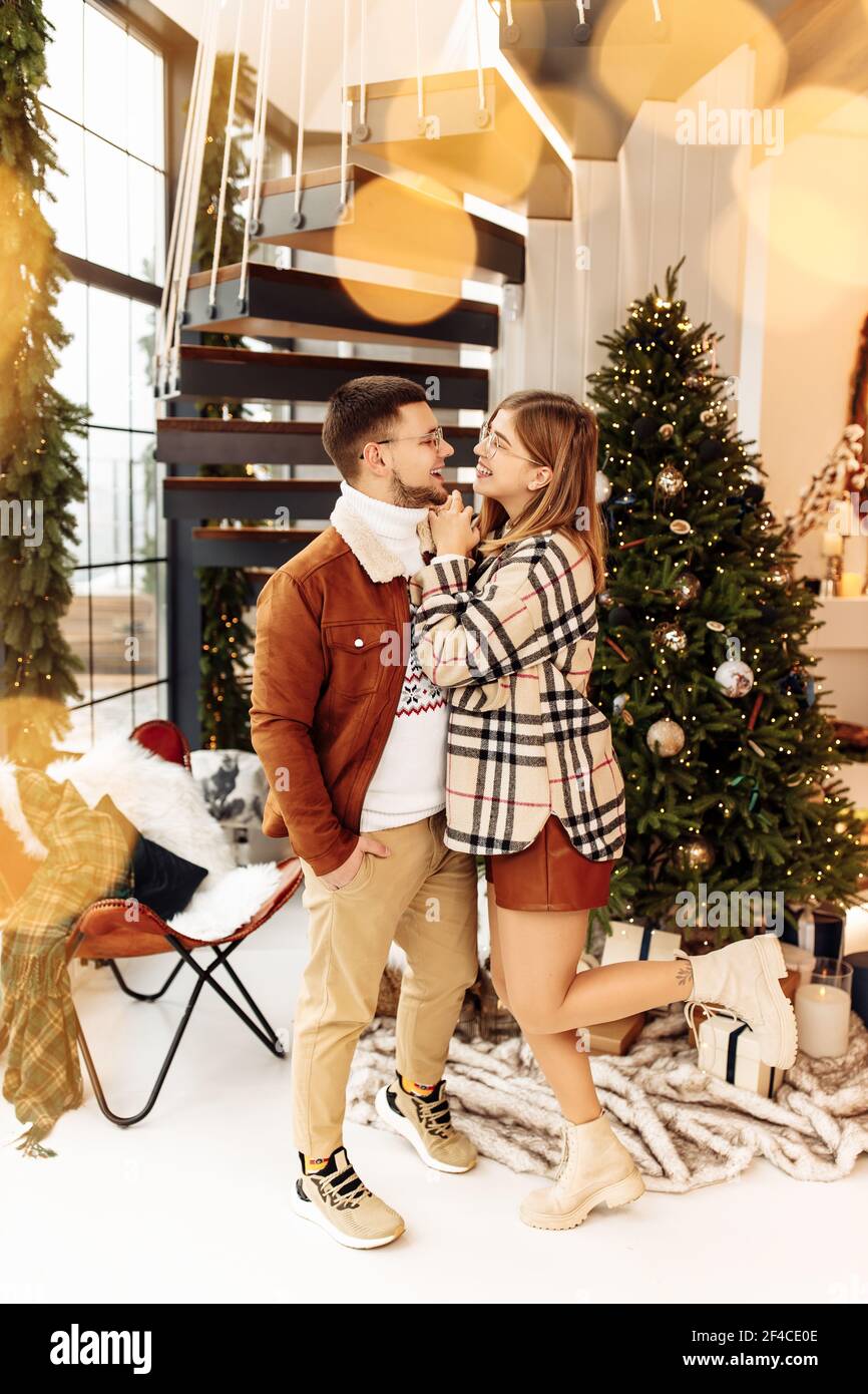 Beautiful couple stand near Christmas tree, cuddling, charming husband ...