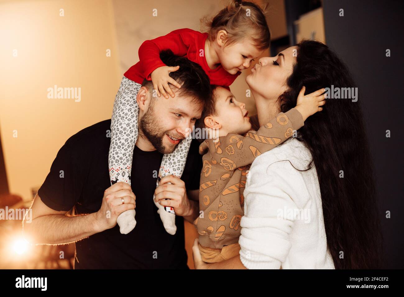 Portrait of overjoyed parents with little kids at home, smiling and ...