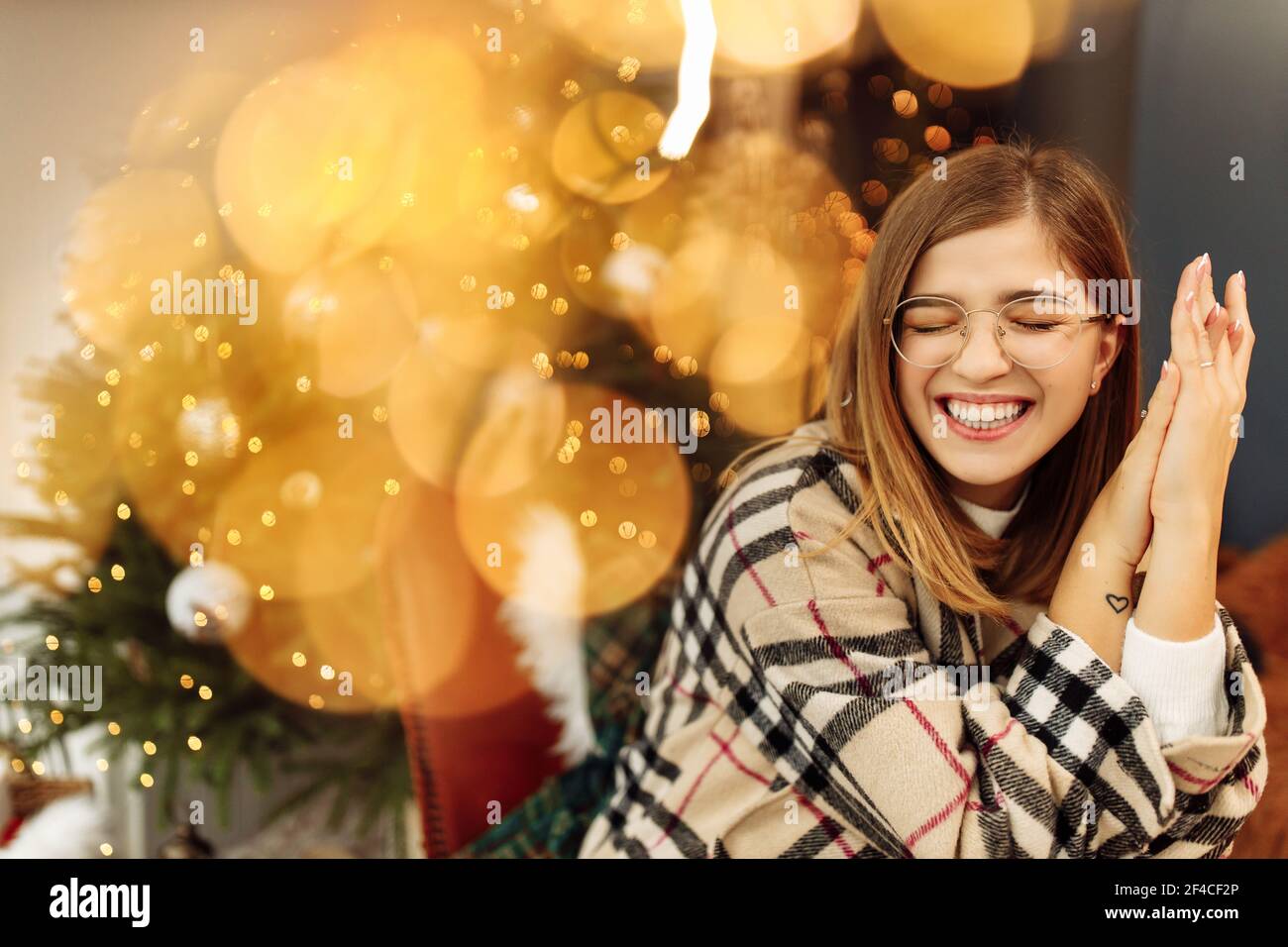 Portrait of smiling lady in glasses sitting near decorated Christmas ...