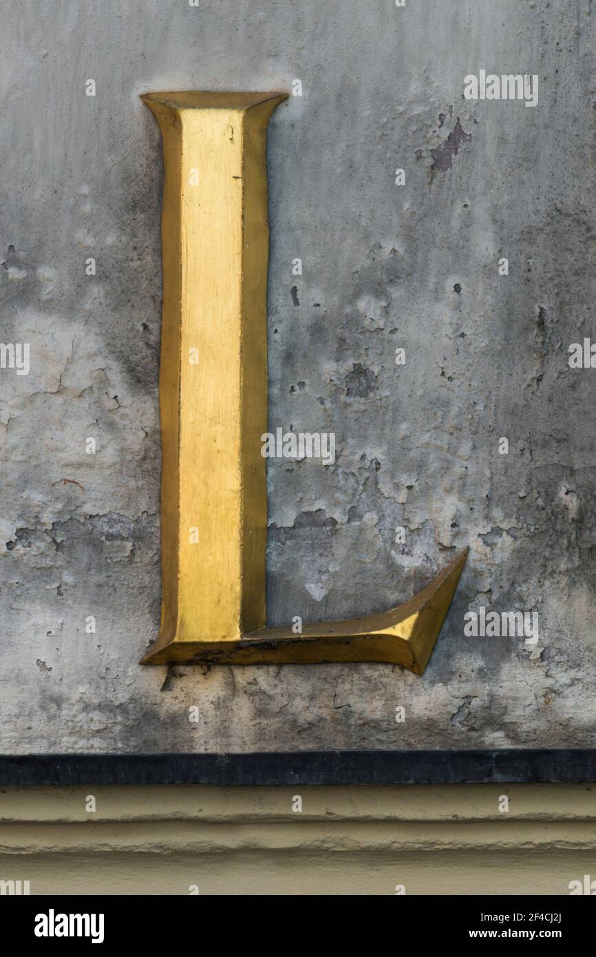 Historic golden letter L with serifs on a grey wall Stock Photo - Alamy