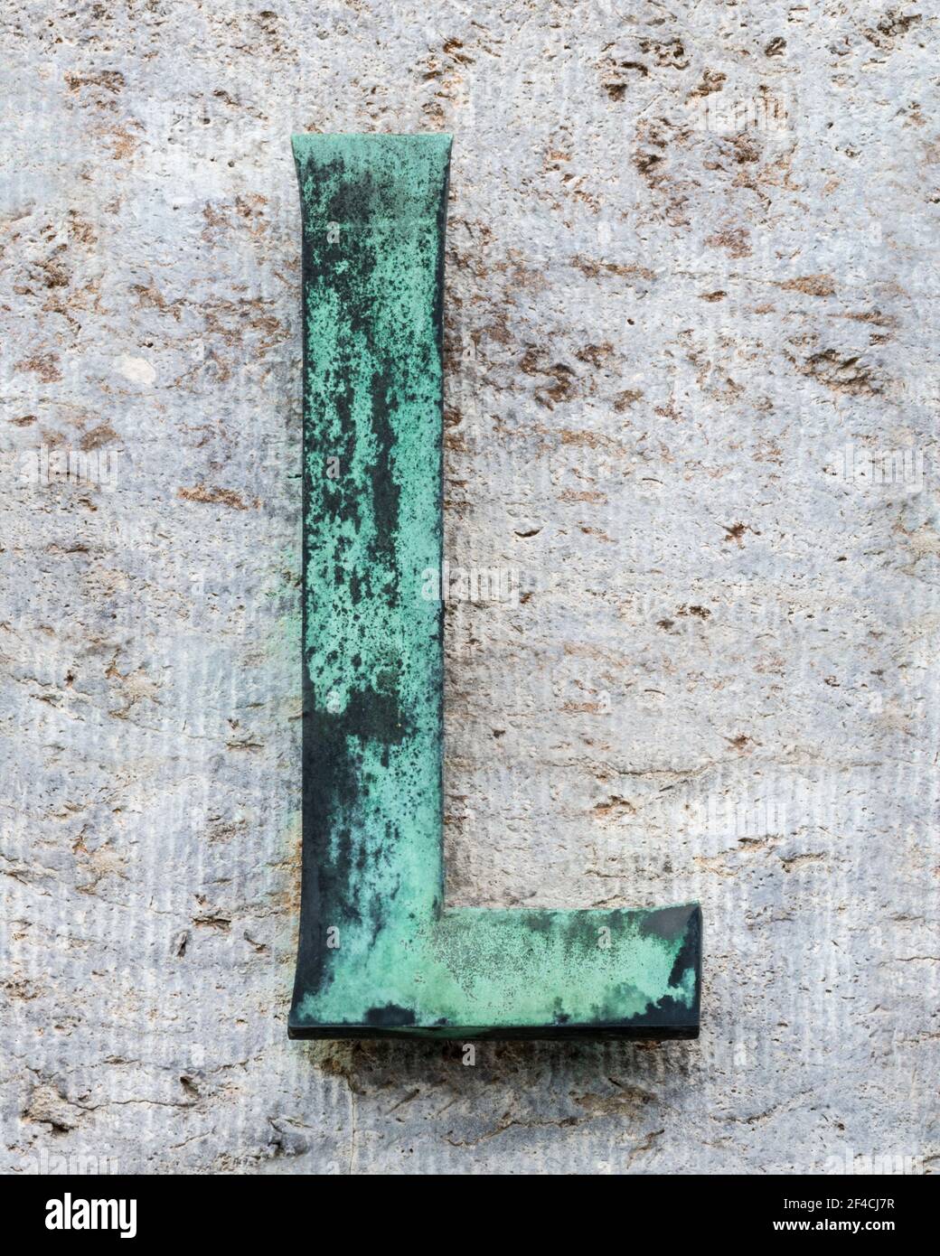Metal letter L covered with verdigris on a natural stone wall Stock ...
