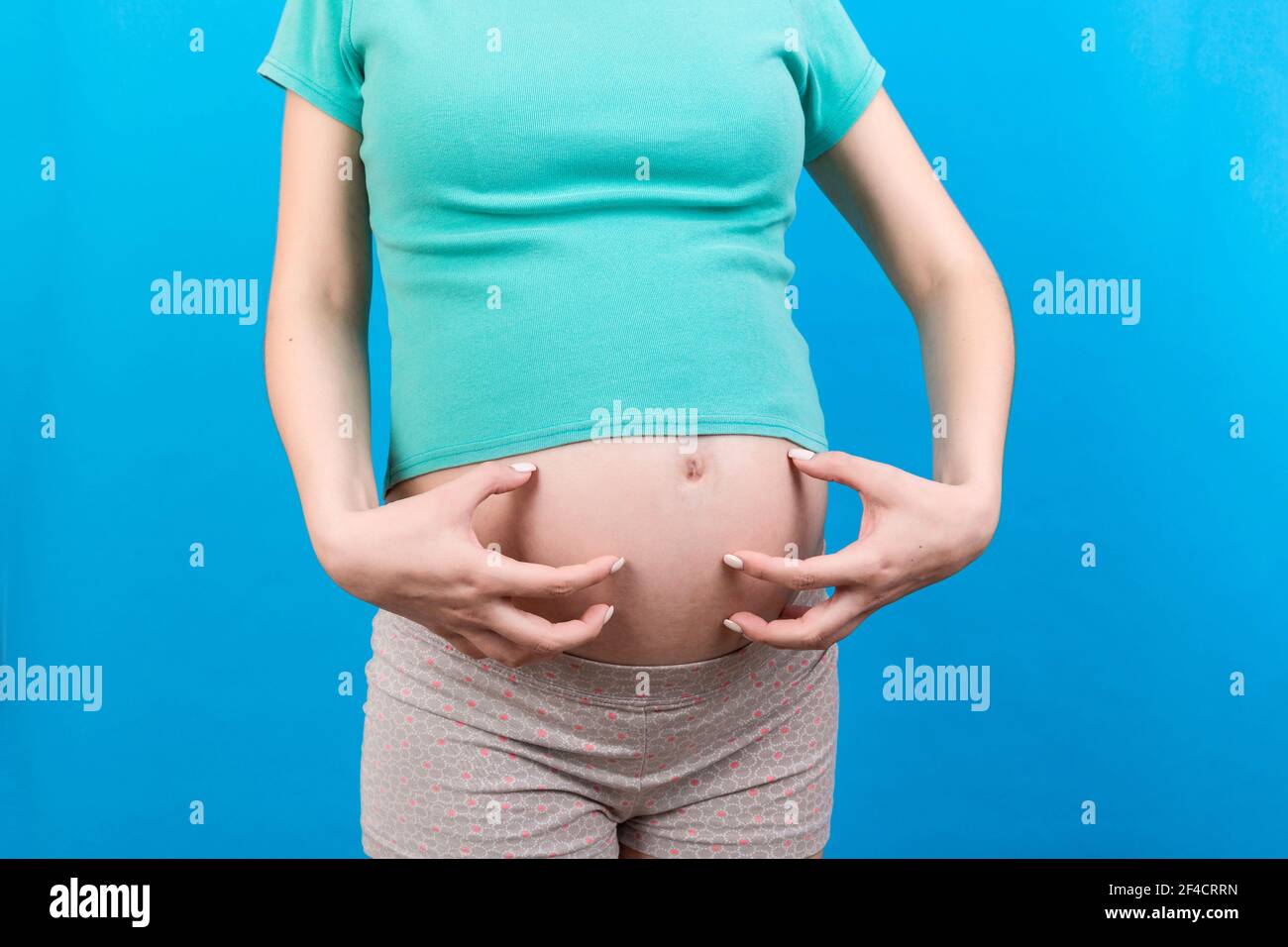 Pregnant woman scratching her belly on colored background Stock Photo ...
