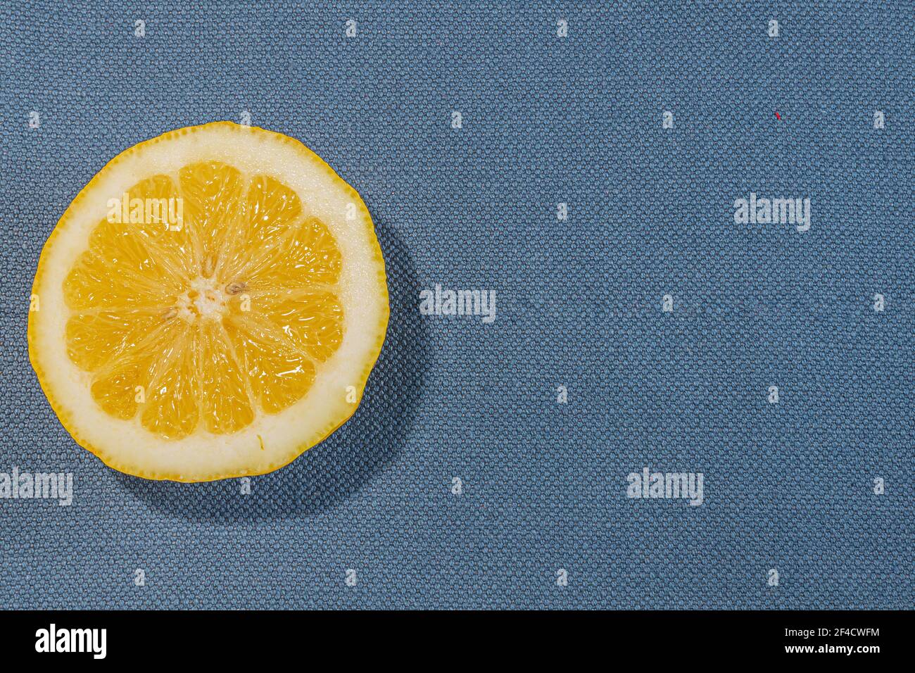 Detail of fresh sliced lemon on a rustic canvas fabric texture in light ...