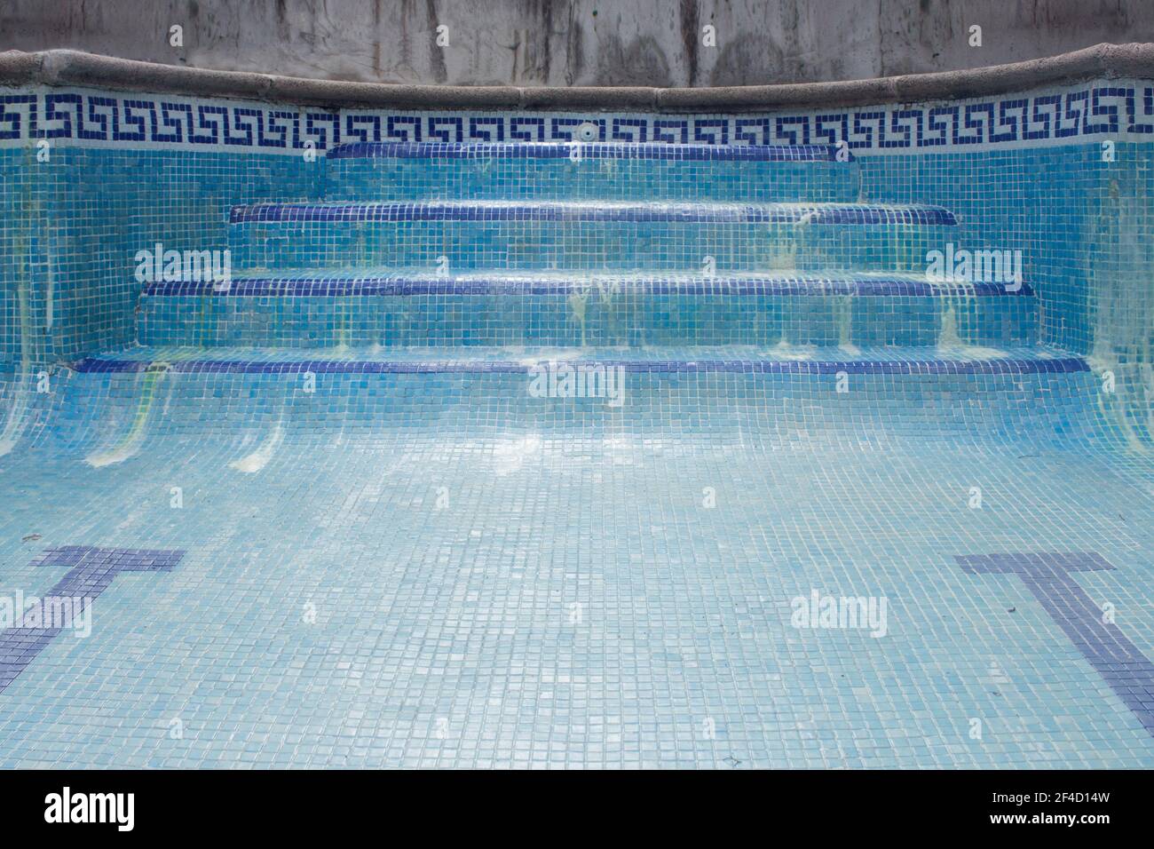 Blue tile swimming pool stairs ladder without water with rests of ...