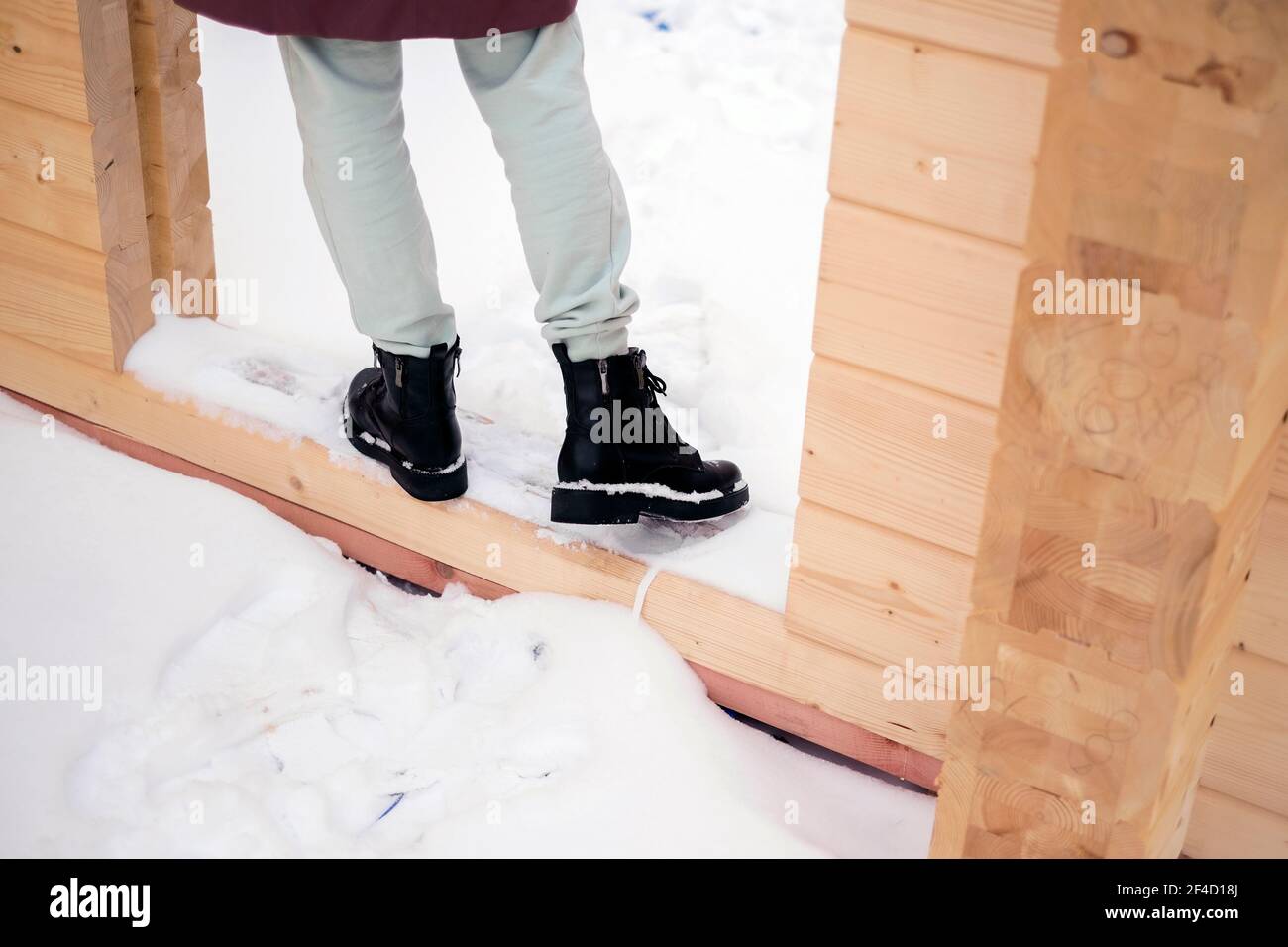 Female legs in boots stepping over a doorway of unfinished house ...