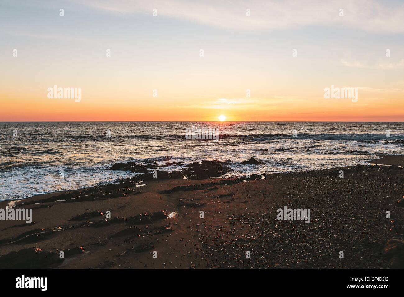 A beautiful quiet and calm beach during an orange sunset Stock Photo ...