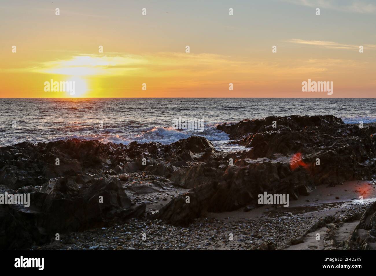 A beautiful quiet and calm beach during an orange sunset Stock Photo ...