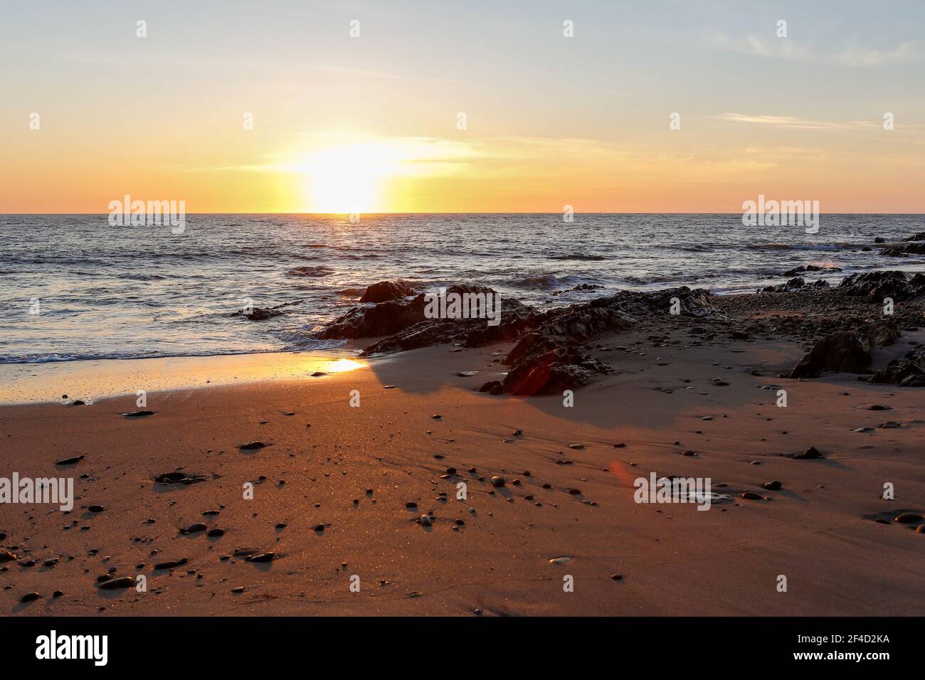 A beautiful quiet and calm beach during an orange sunset Stock Photo ...