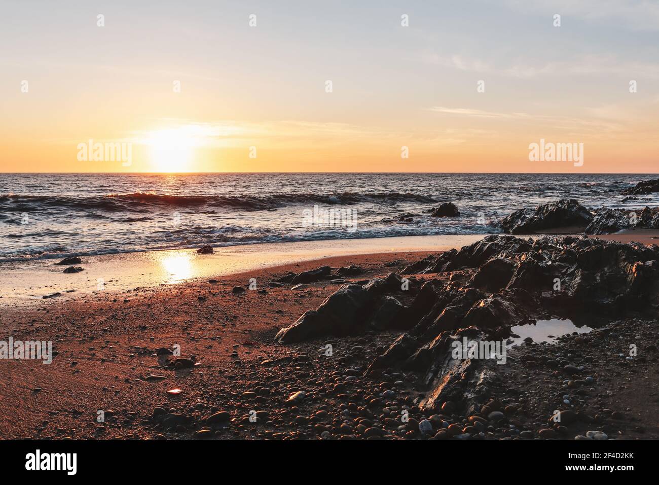 A beautiful quiet and calm beach during an orange sunset Stock Photo ...