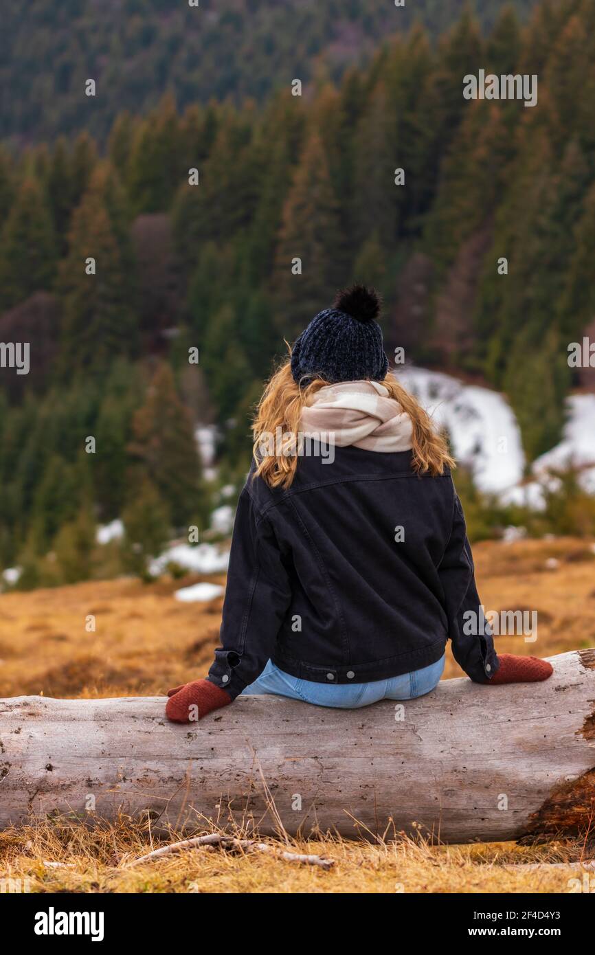 A girl sitting on a log and looking at the forest. Freedom on the ...