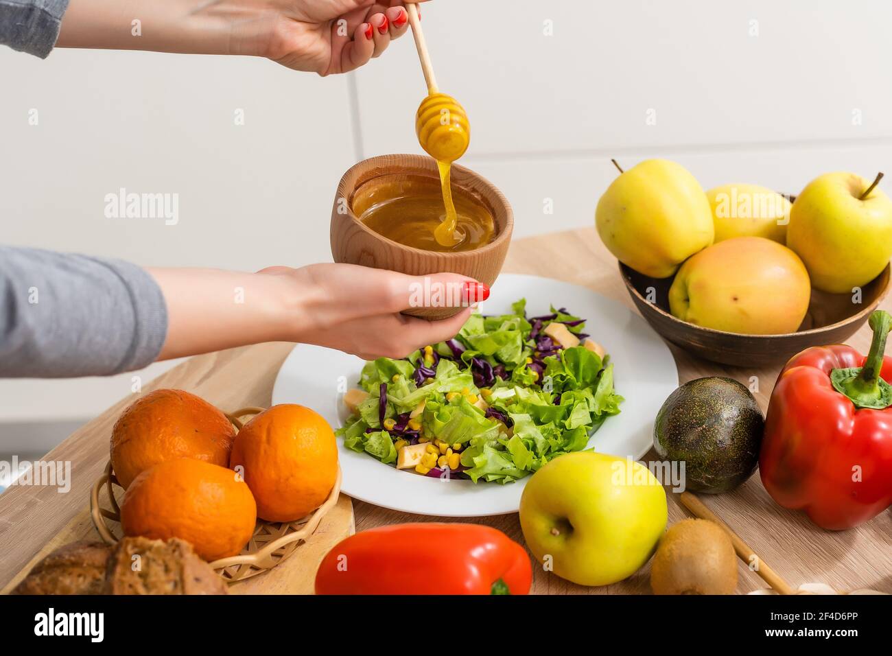 Woman pouring honey mustard dressing into bowl with fresh salad on ...