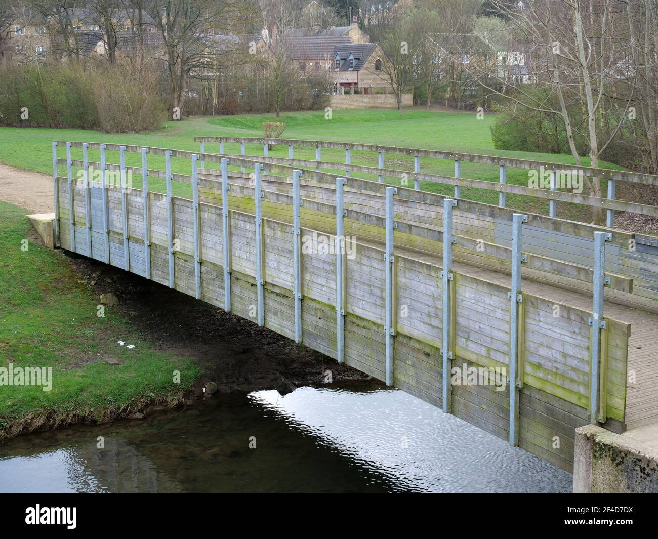 Wooden footbridge over small river with grassy bank Stock Photo - Alamy