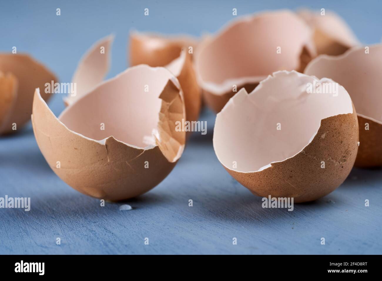Broken egg shells on blue background Stock Photo - Alamy