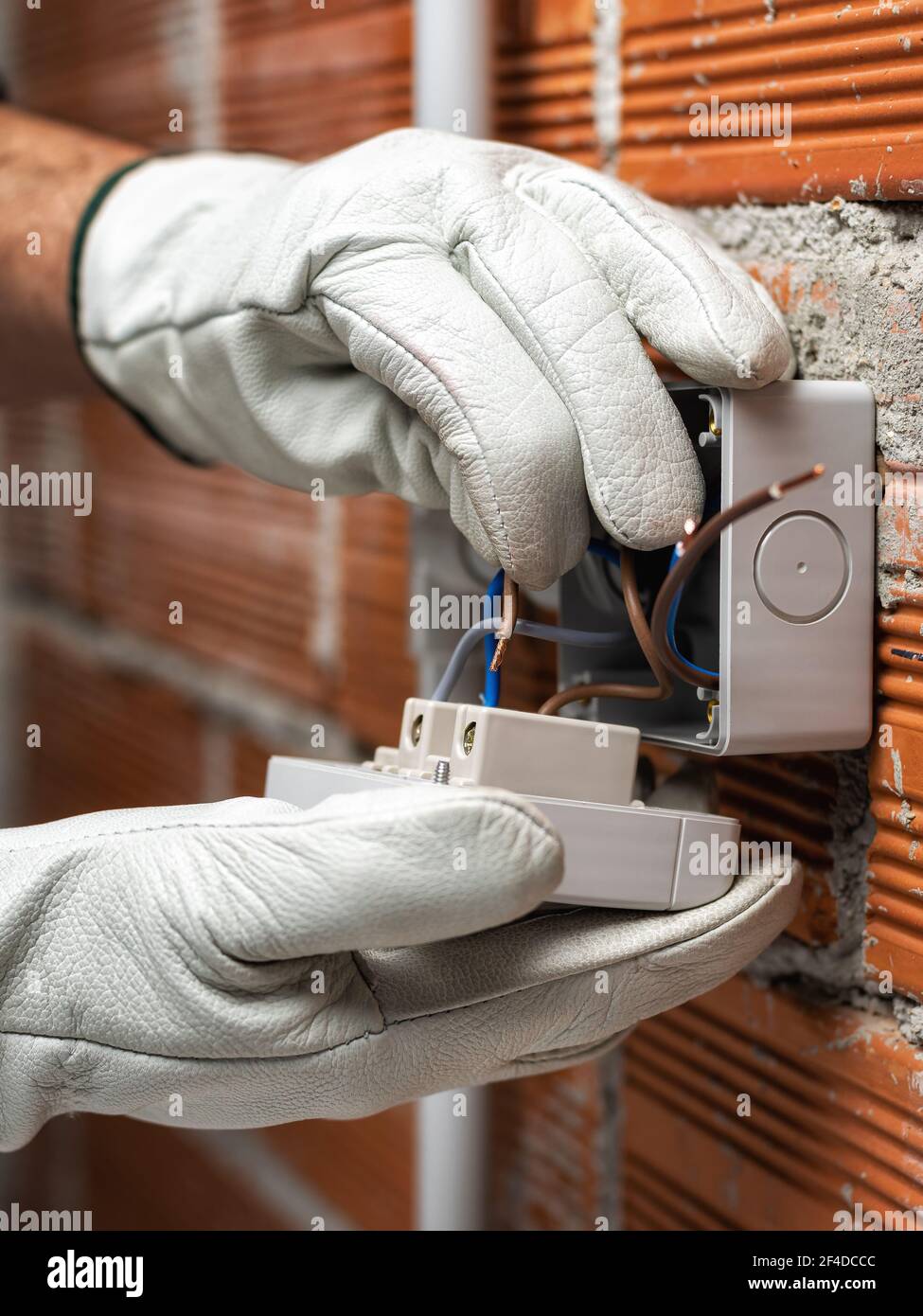 Electrician worker at work inserts the electrical cable into the clamp ...