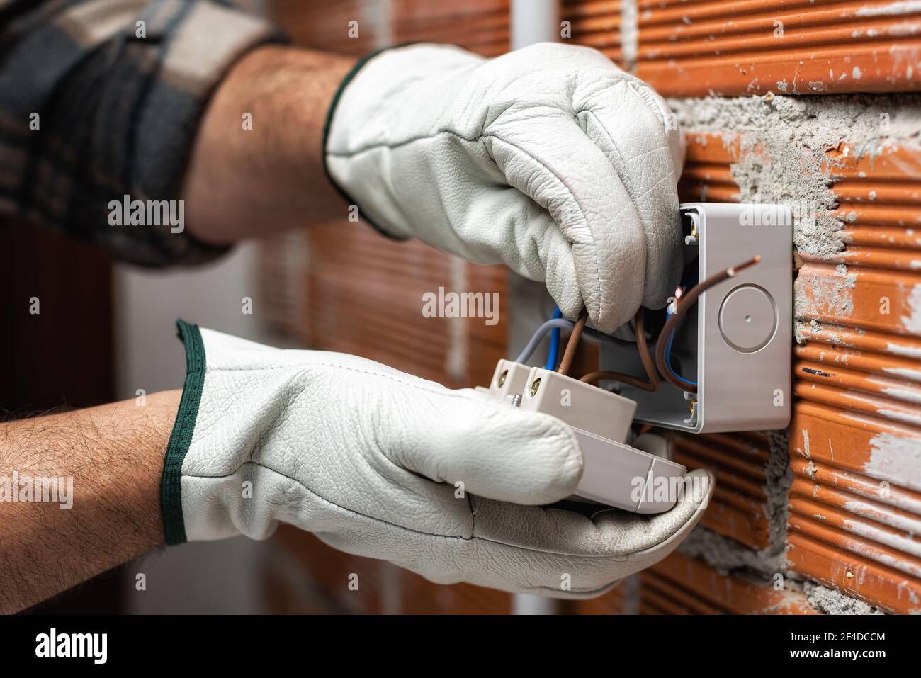 Electrician worker at work inserts the electrical cable into the clamp ...