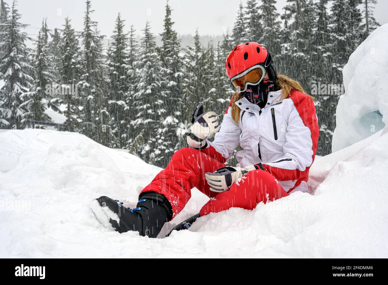 Skier woman in heavy snowfall, wearing a snowsuit sitting in the snow ...