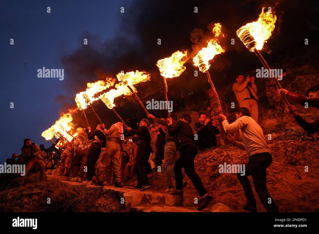 Akre, Iraq. 20th Mar, 2021. Iraqi Kurdish men hold fire torches during ...