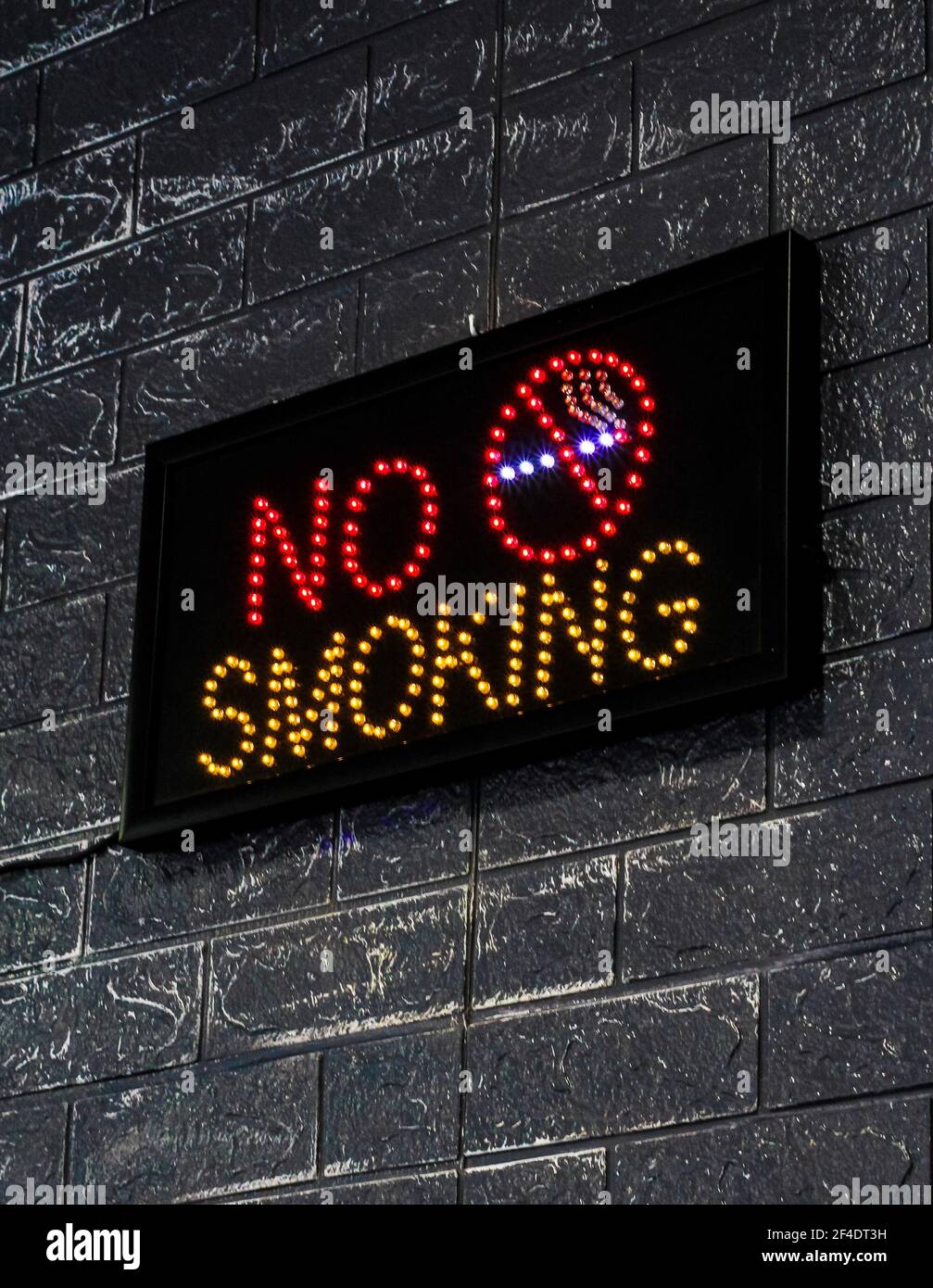 A vertical shot of a "NO SMOKING" sign with led lights on the wall ...