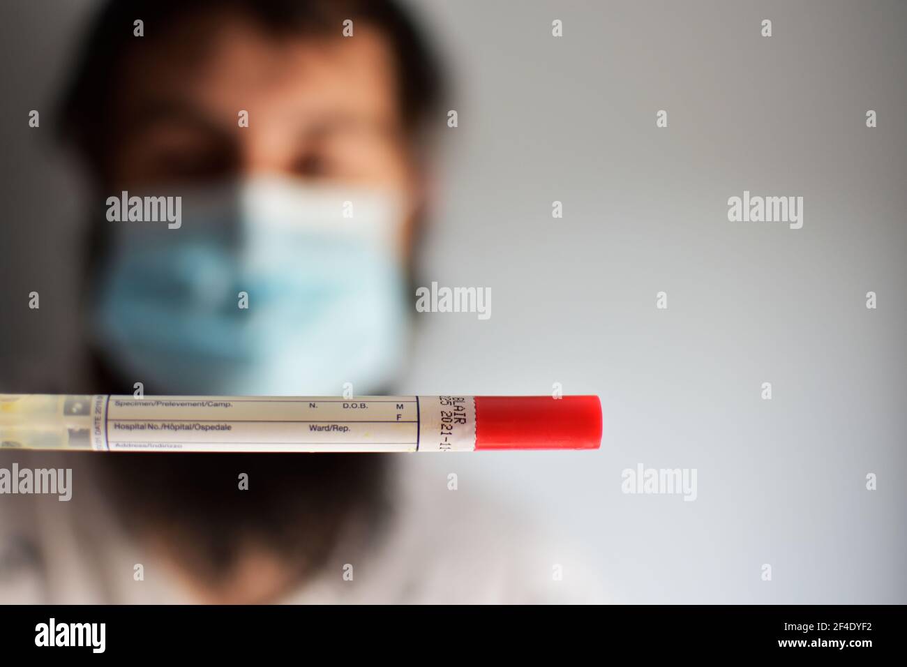 Nurse holding a tube. Rotavirus test. Man wearing a face mask grabbing ...