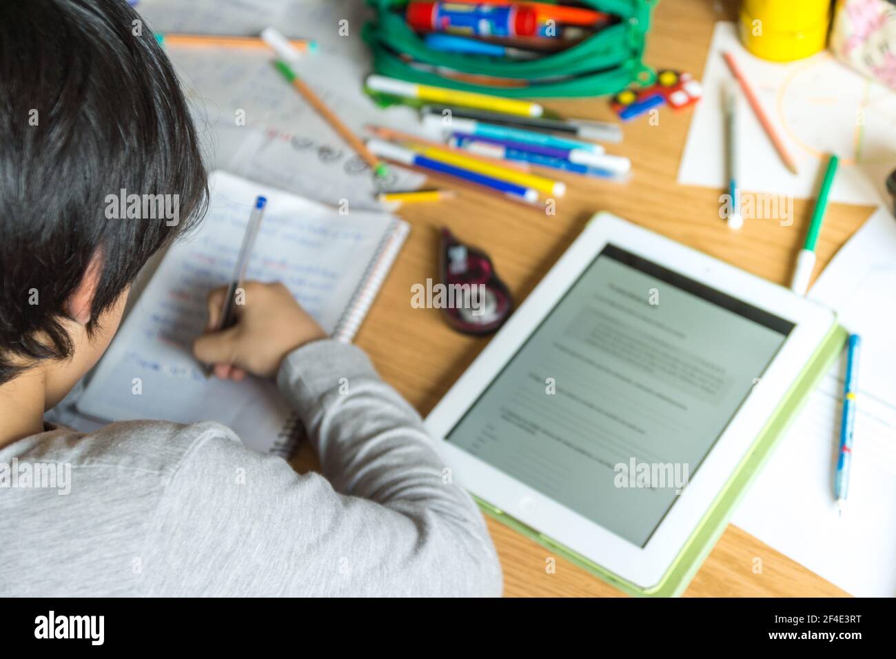 side image with natural light of boy doing homework with a notebook and ...