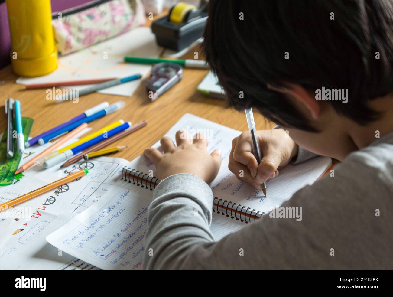 natural light side image of boy doing homework in a notebook on brown ...