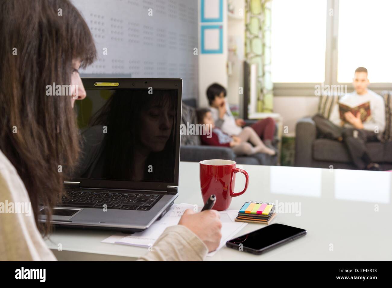 mother teleworking with laptop and office supplies on white table and ...