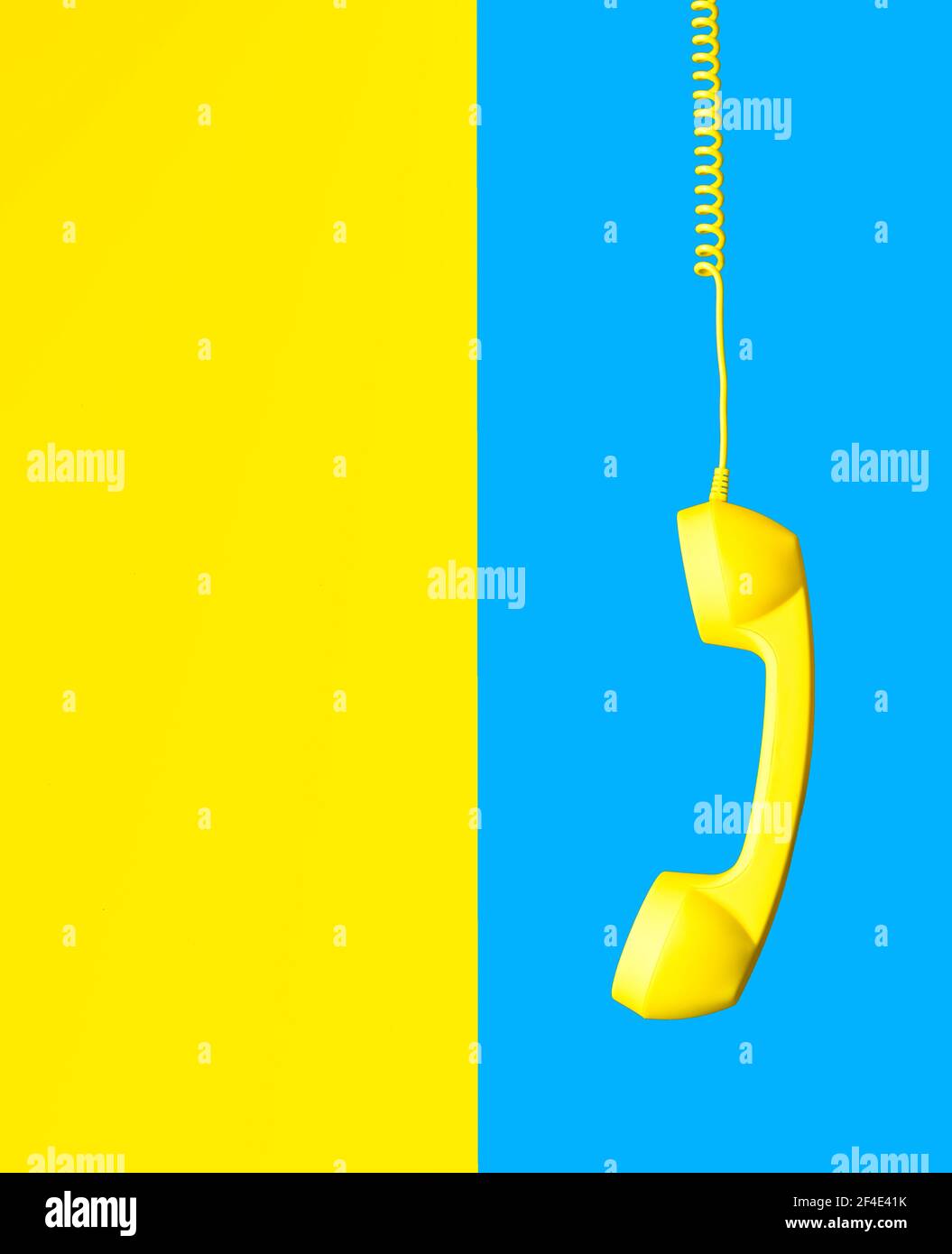 yellow retro phone hanging on spiral cord on background split in half ...