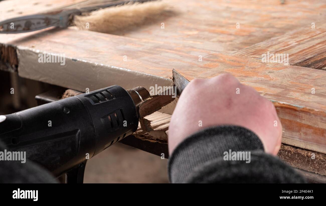 craftsman removes the old paint from the wooden door spatula and ...