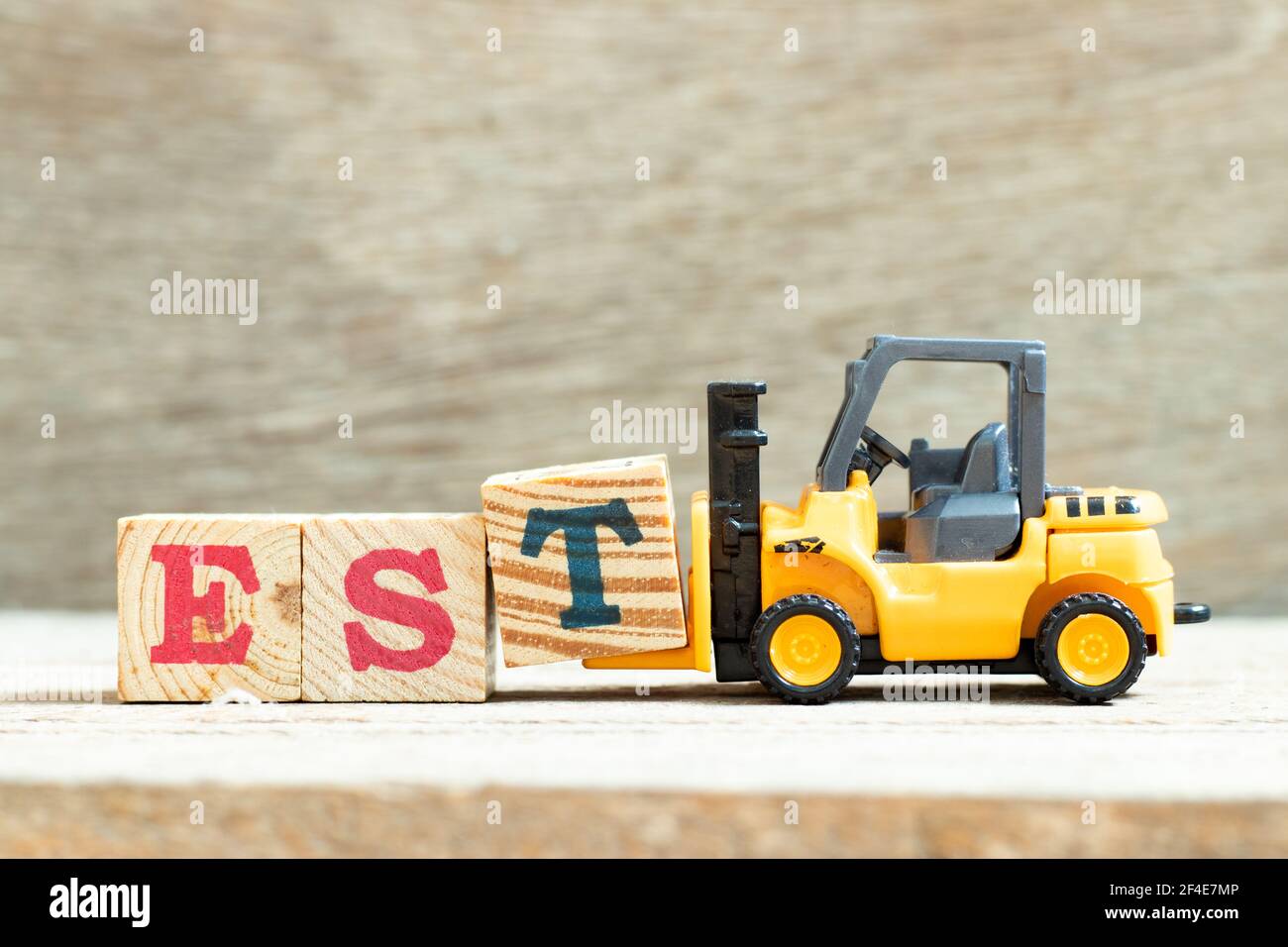Toy forklift hold letter block t to complete word EST (abbreviation of ...