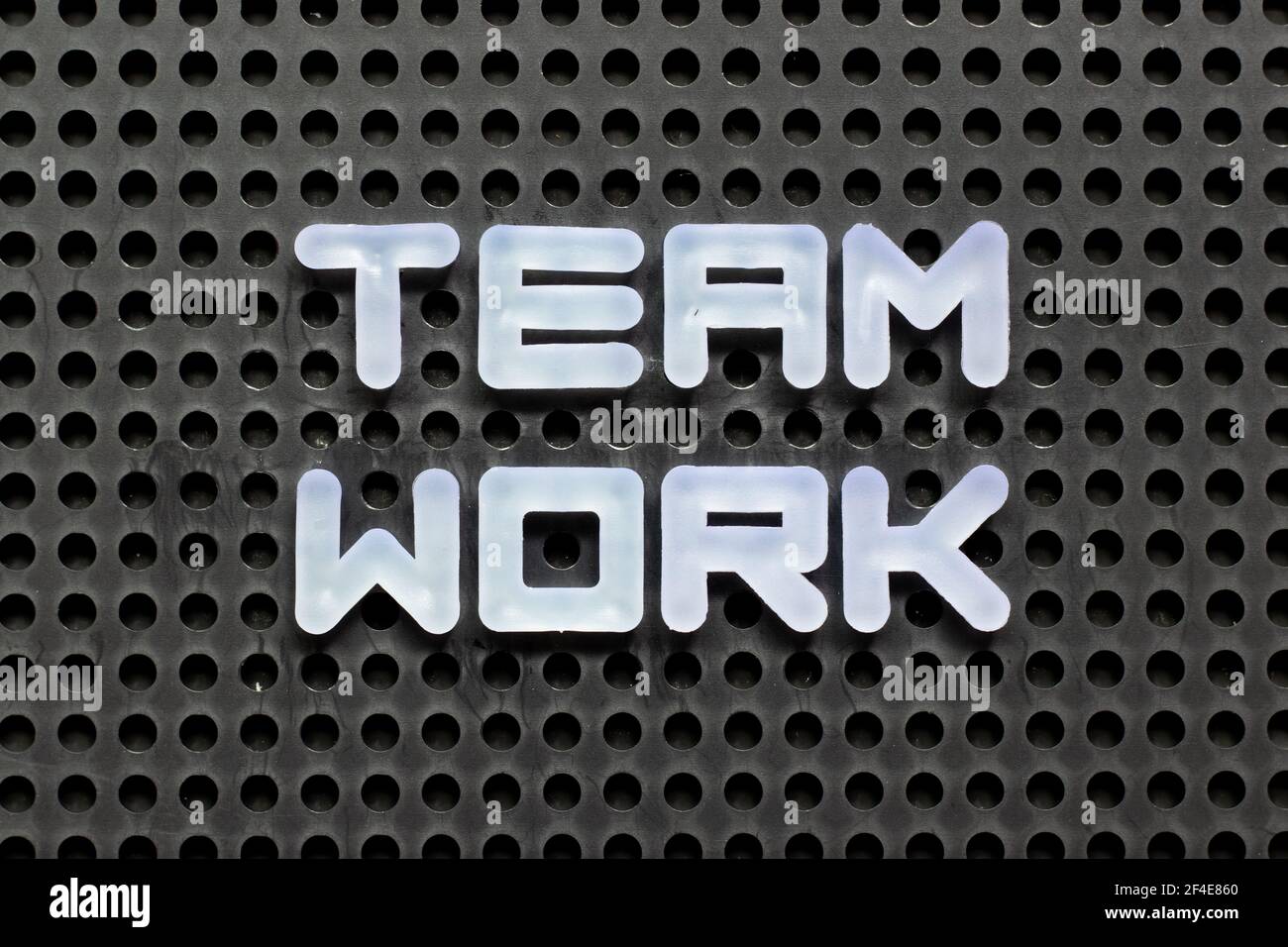 White color letter in word teamwork on black pegboard background Stock ...