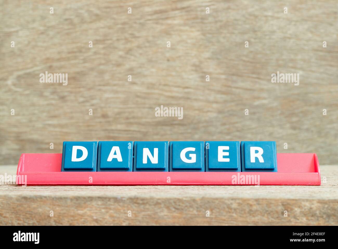 Tile alphabet letter with word danger in red color rack on wood ...