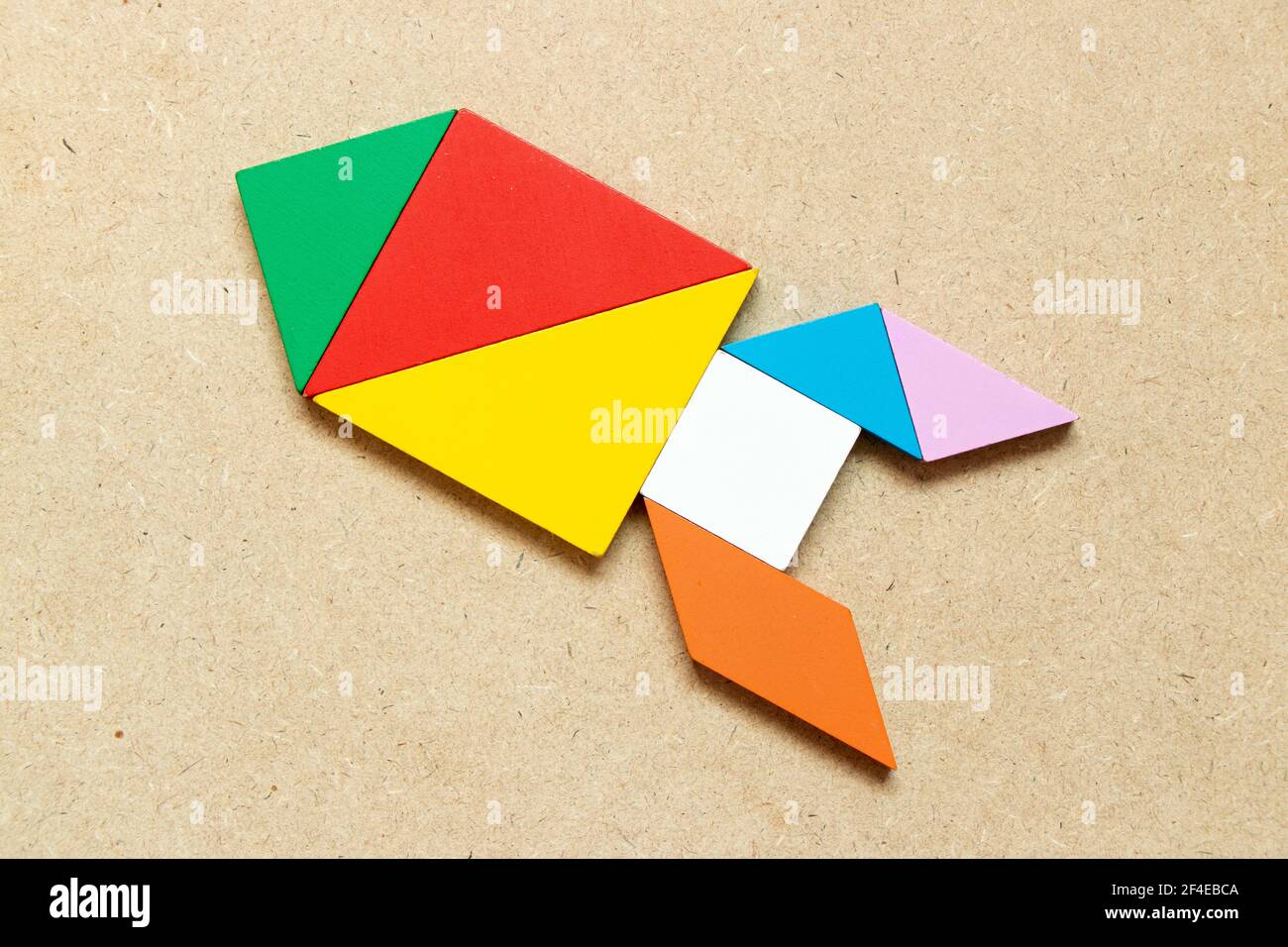 Color tangram puzzle in missile or rocket shape on wood background ...