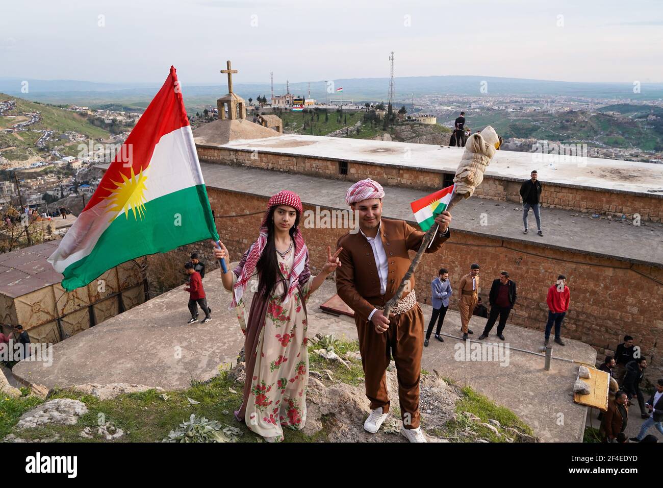 Akre, Iraq. 20th Mar, 2021. A man carrying a torches stands with a girl ...