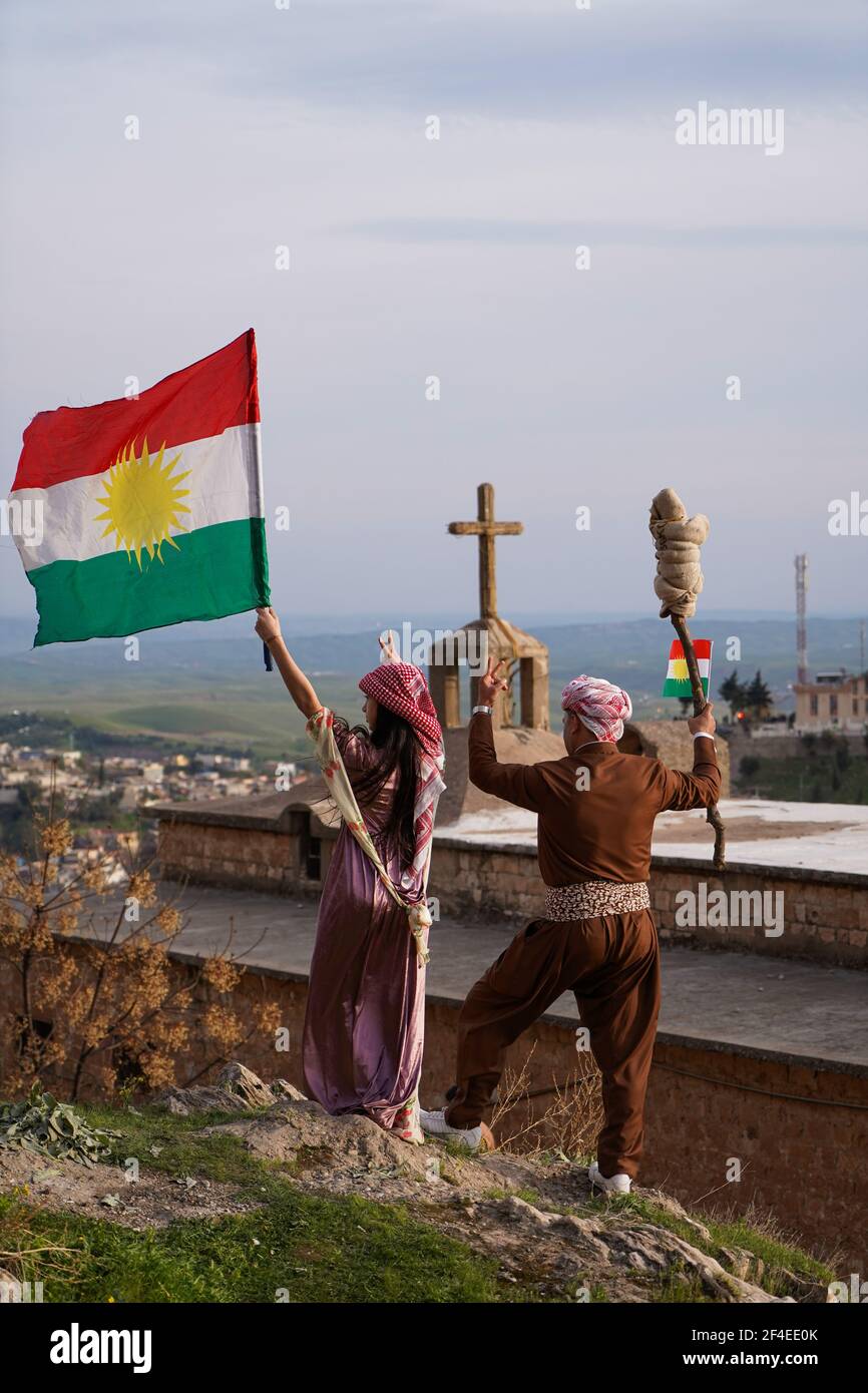 Akre, Iraq. 20th Mar, 2021. A man carrying a torches stands with a girl ...